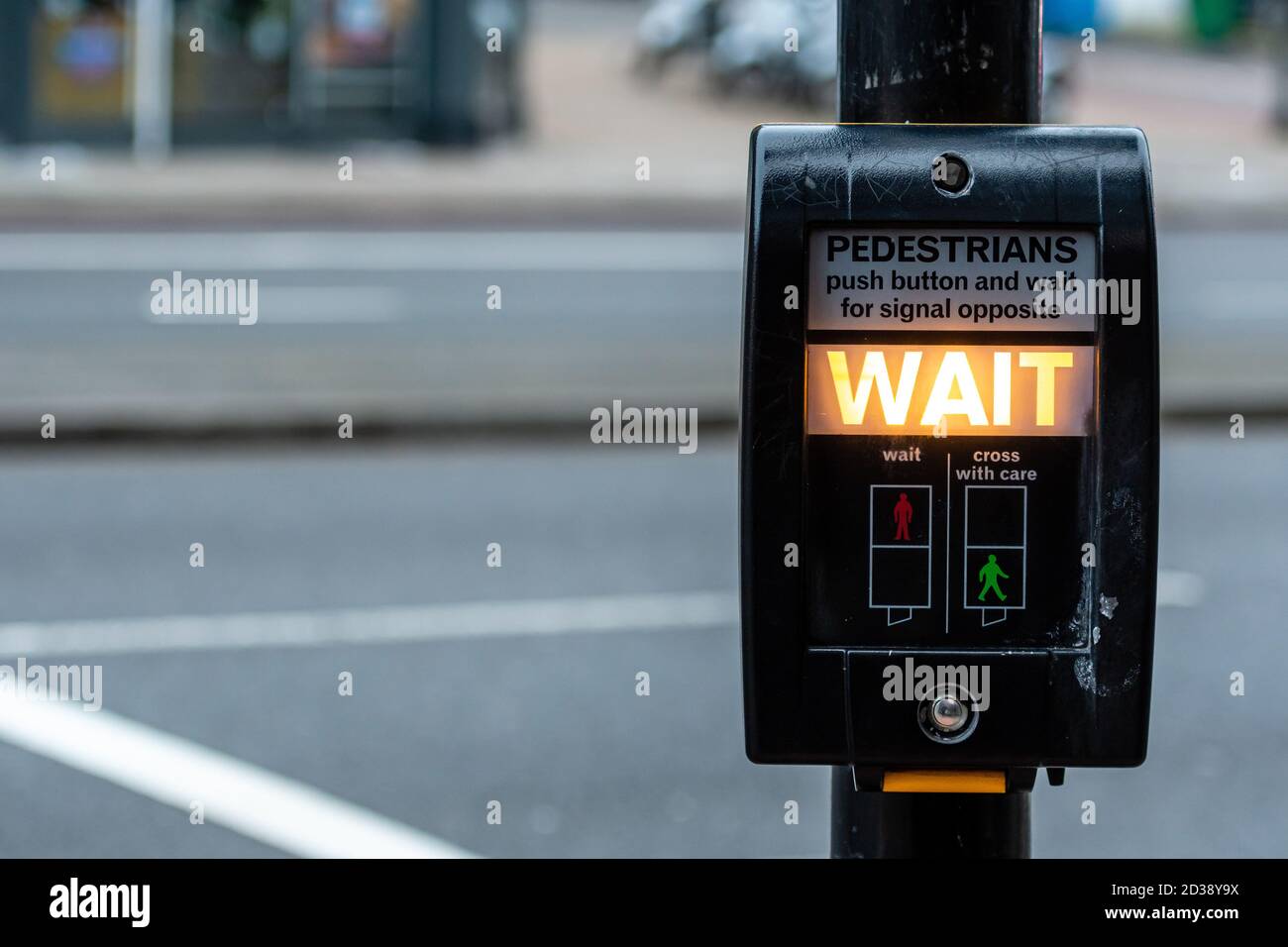 Crosswalk button for pedestrian with light warning on a defocused ...