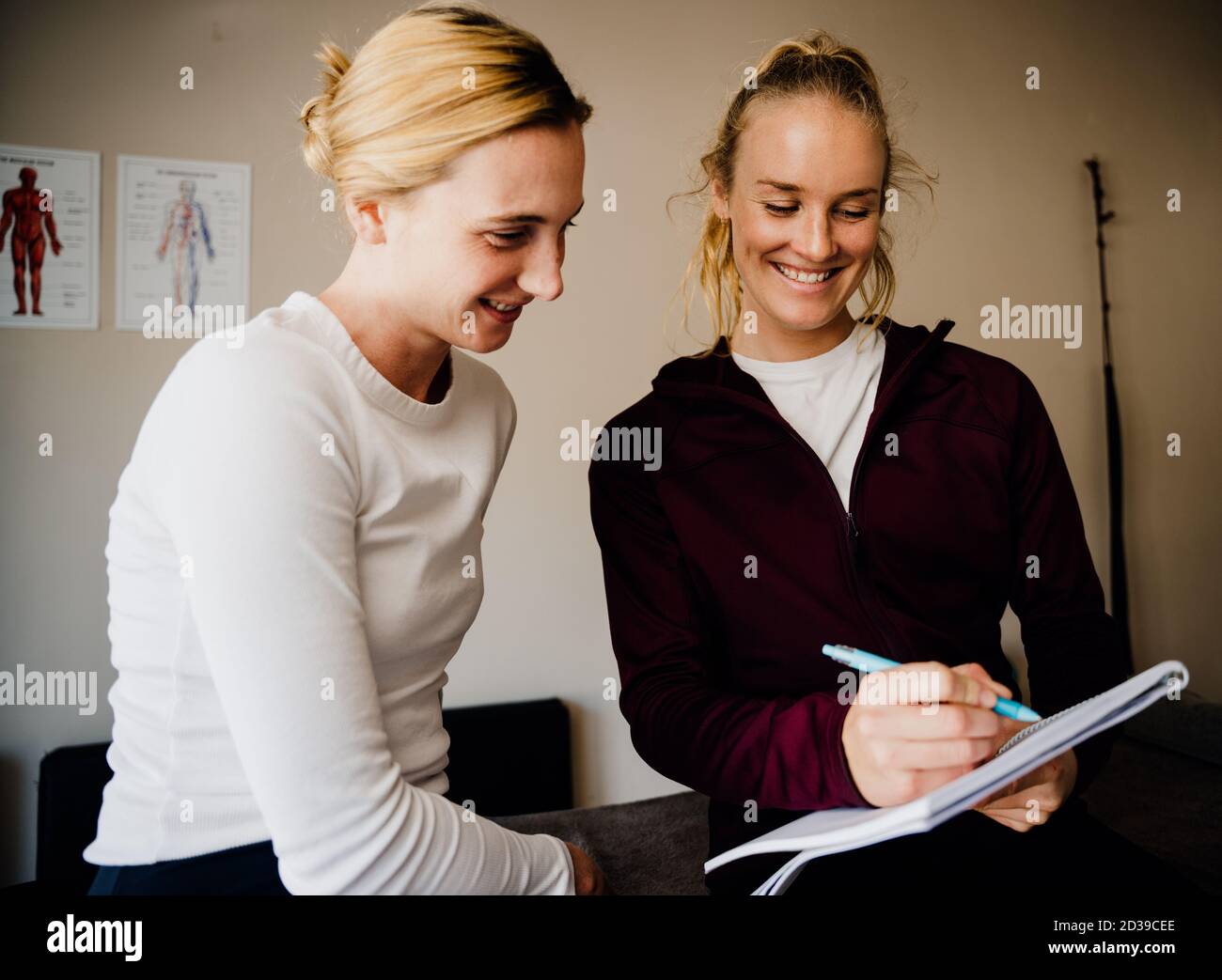 young caucasian physiotherapist pointing with pen to paper while woman ...