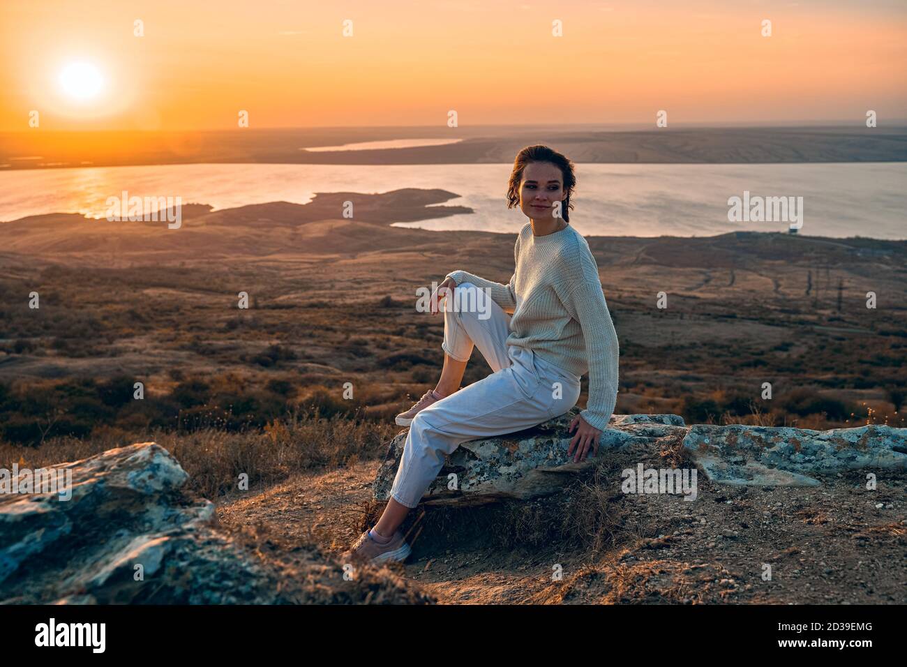 beautiful girl on a rock in the sunset background Stock Photo - Alamy