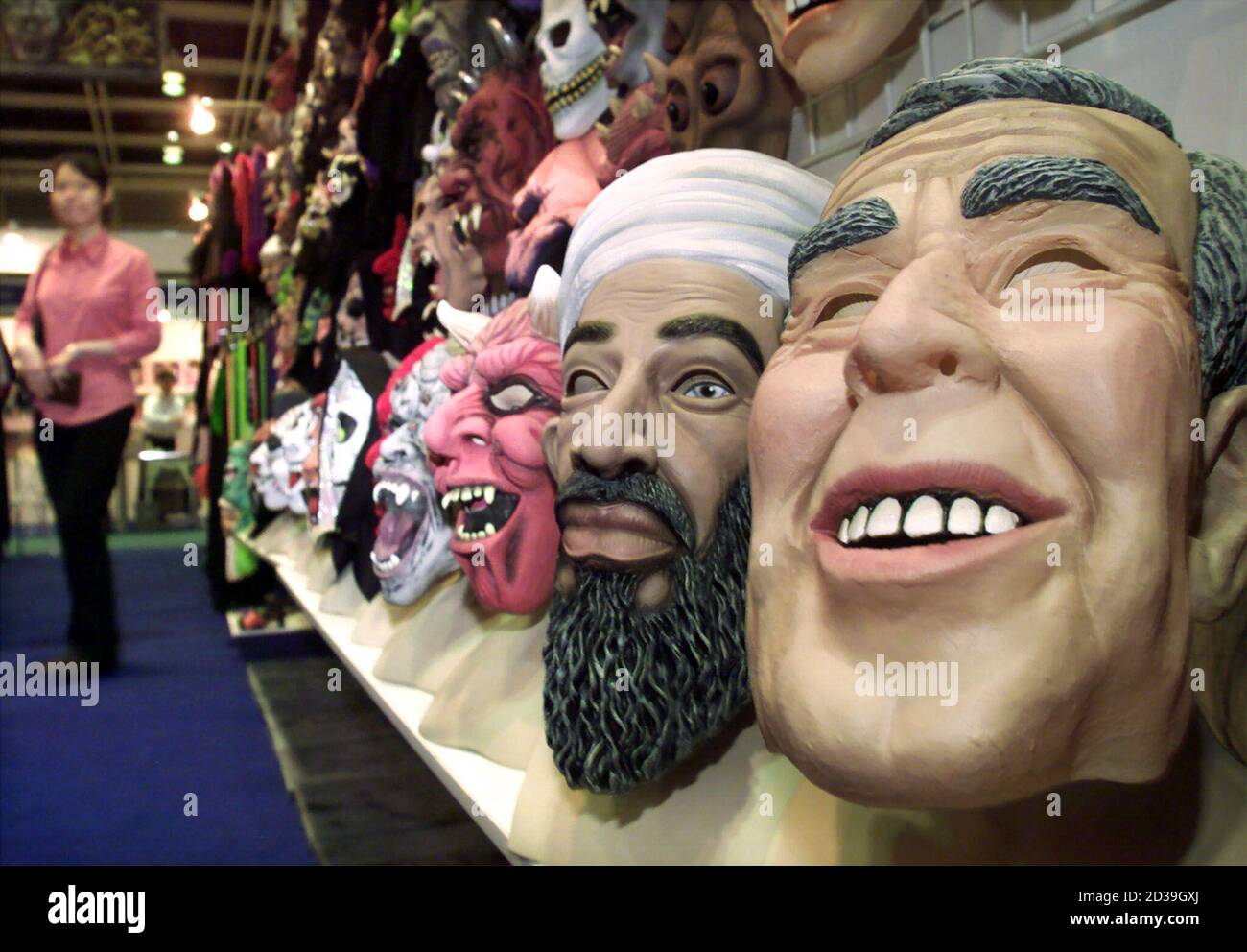A potential client walks through a booth displaying the masks of Osama ...