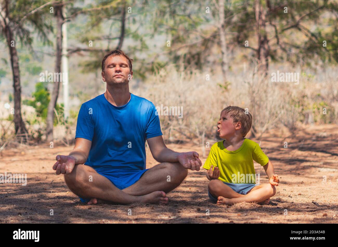 Father meditates yoga pose close eyes in forest park fresh air, son ...