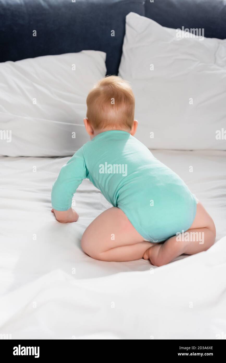 back view of infant kid in baby romper crawling in bed Stock Photo - Alamy