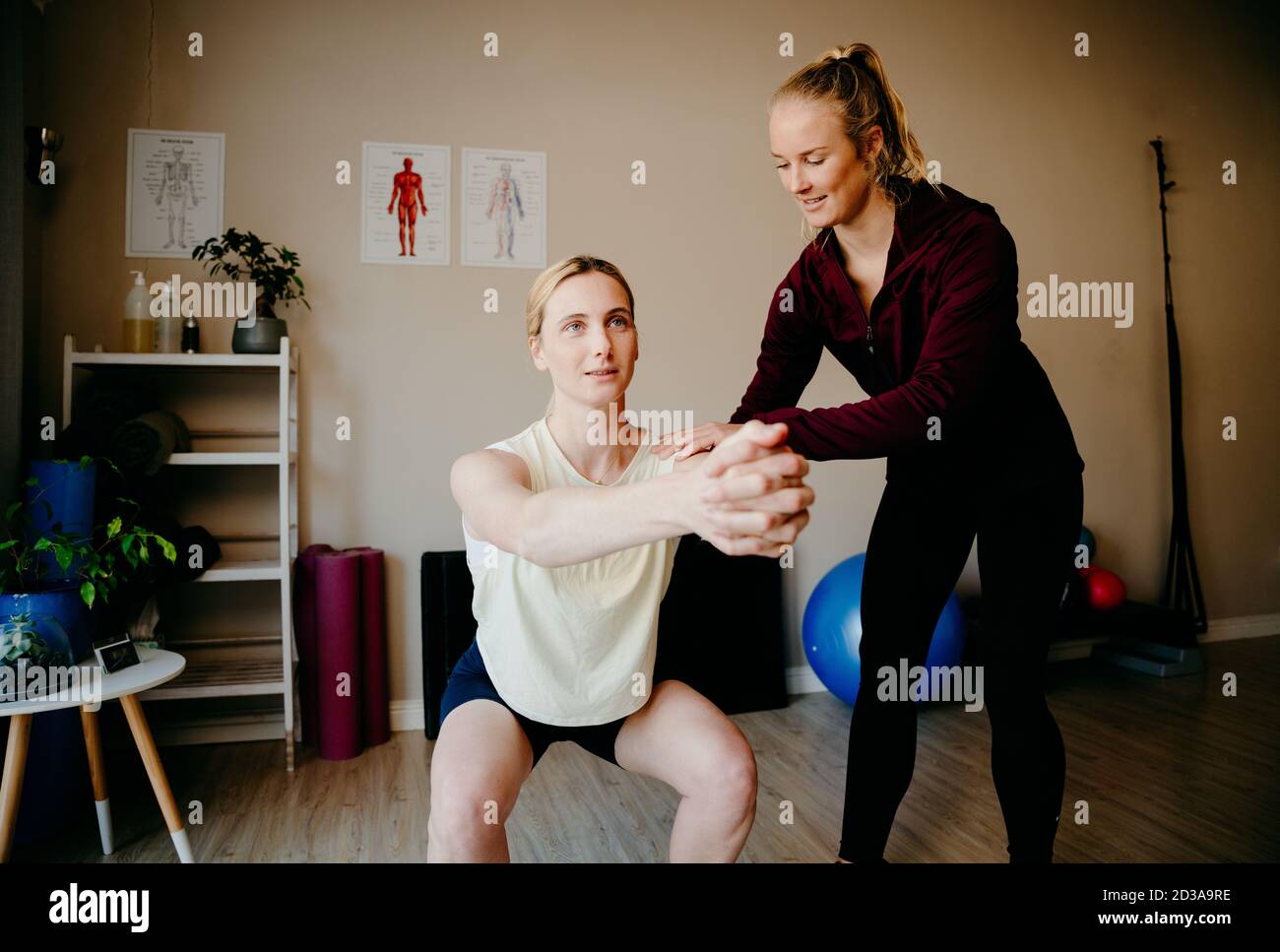Young female patient practising squat position while trained ...
