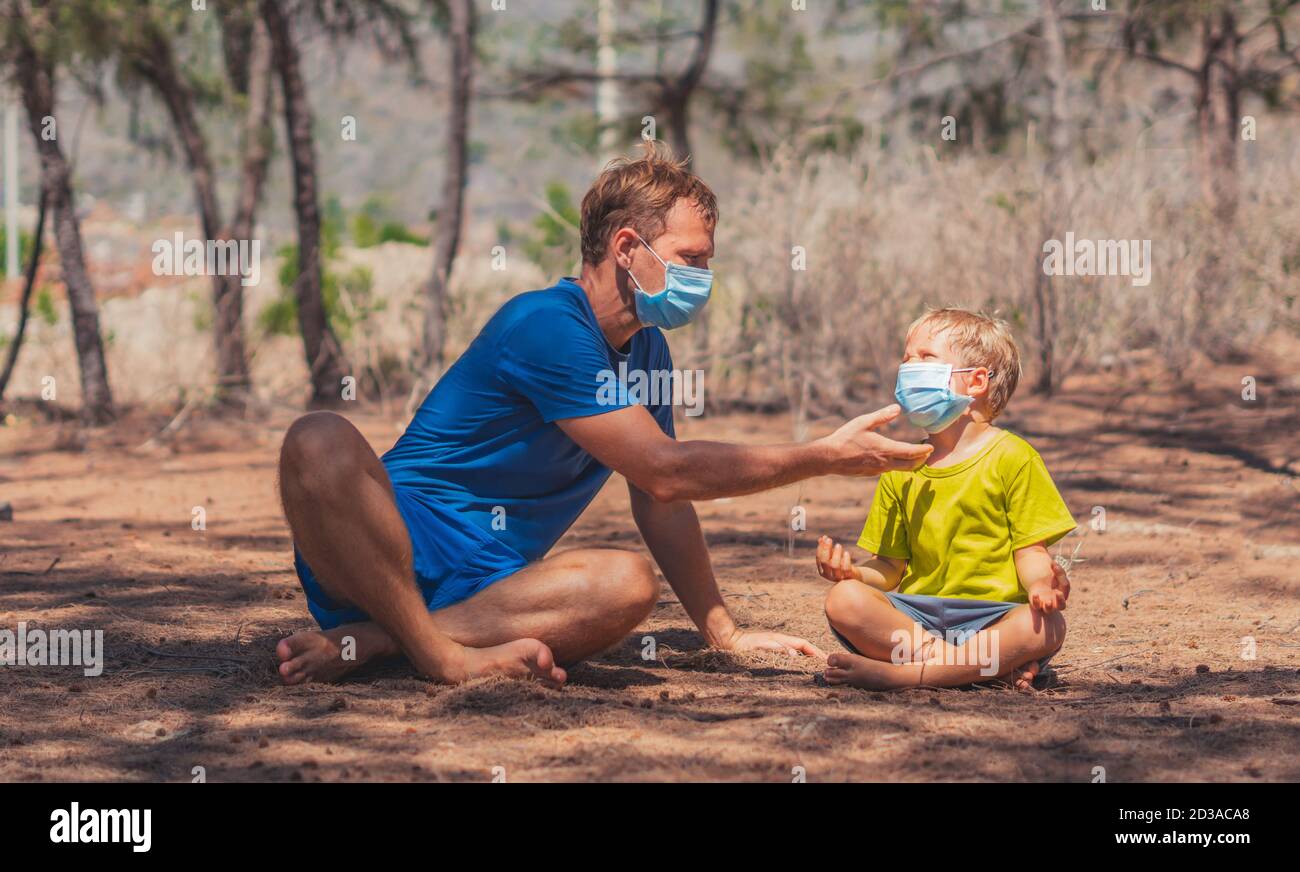 Father meditates yoga pose in forest park fresh air, son repeats, wear ...
