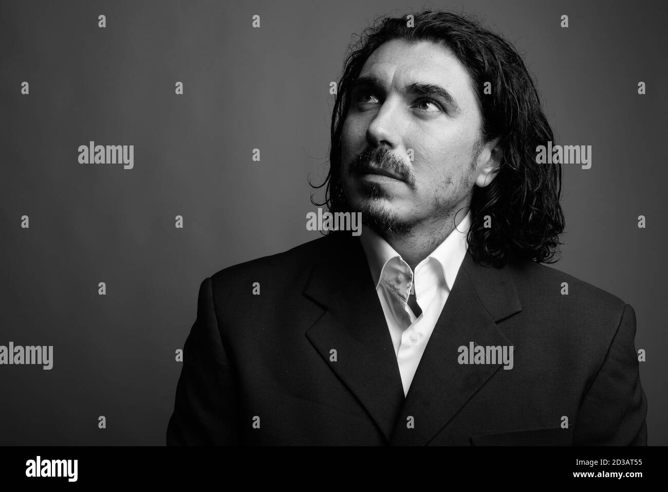 Handsome businessman with mustache wearing suit against gray background ...