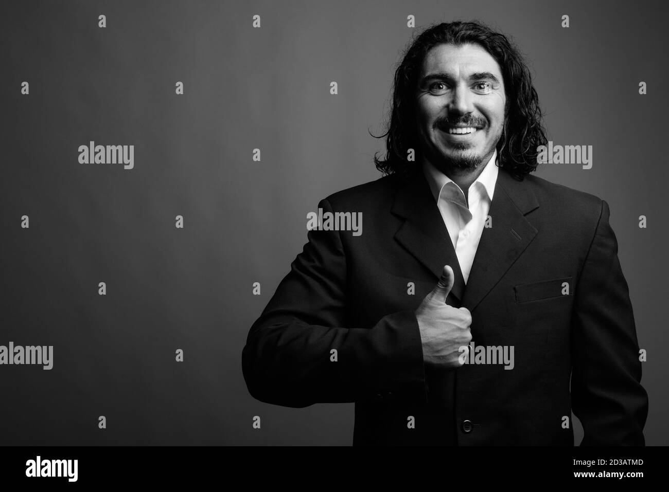 Handsome businessman with mustache wearing suit against gray background ...
