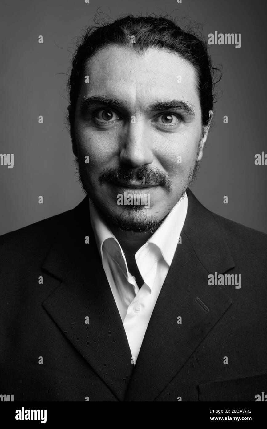 Handsome businessman with mustache wearing suit against gray background ...