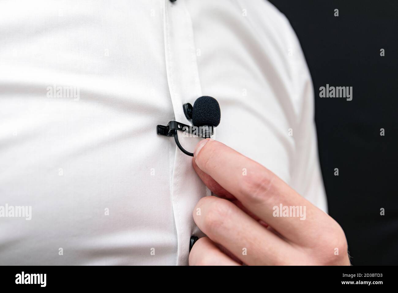 A man dressing in white shirt holding small lavalier microphone Stock ...