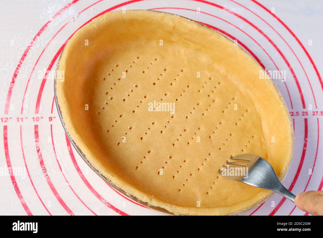 Using fork to poke the holes all over the dough before blind baking ...