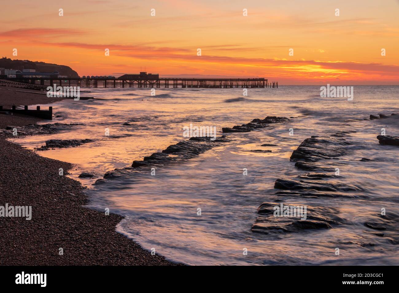 Sun rising behind Hastings pier in east Sussex with the tide receding ...