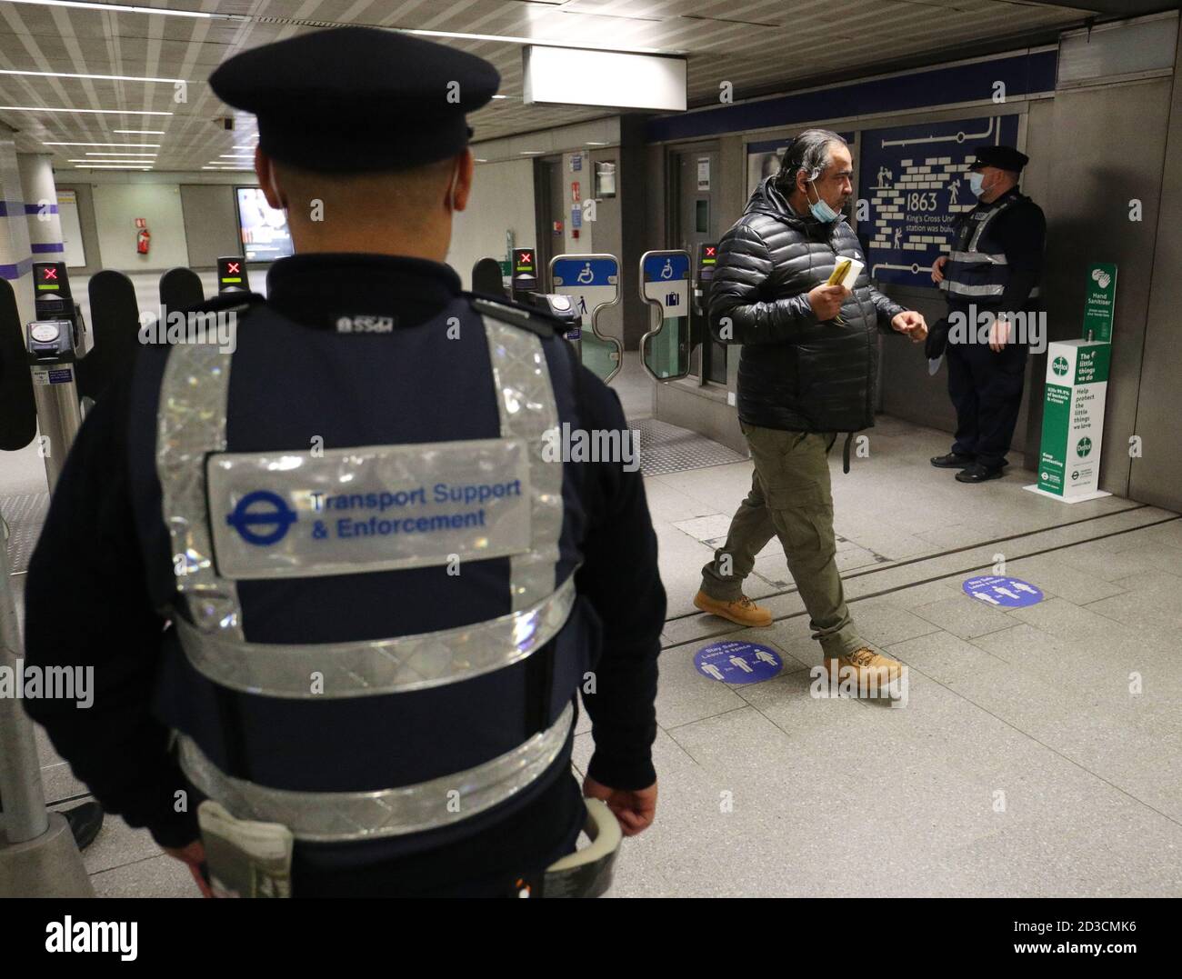 A man with his face mask on his chin walks past TfL Transport Support ...