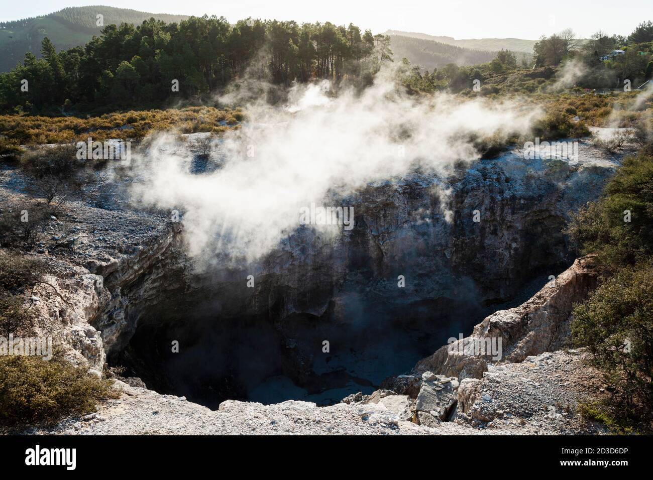 View into a crater with geothermal heat steam rising from the water ...