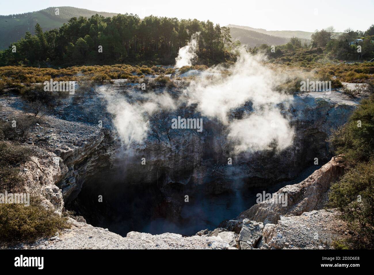 View into a crater with geothermal heat steam rising from the water ...