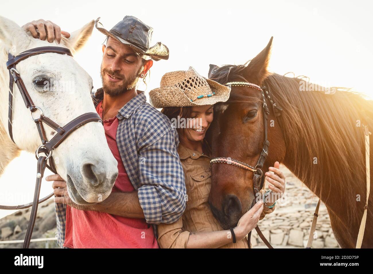 Happy couple having fun with horses inside stable - Young farmers ...