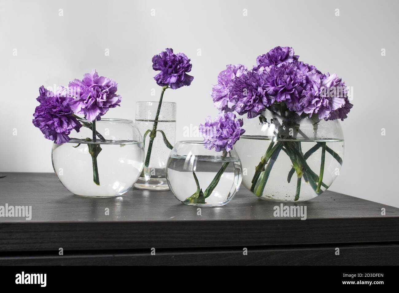 Bridal bouquets of lilac carnations in a four round glass vases ...
