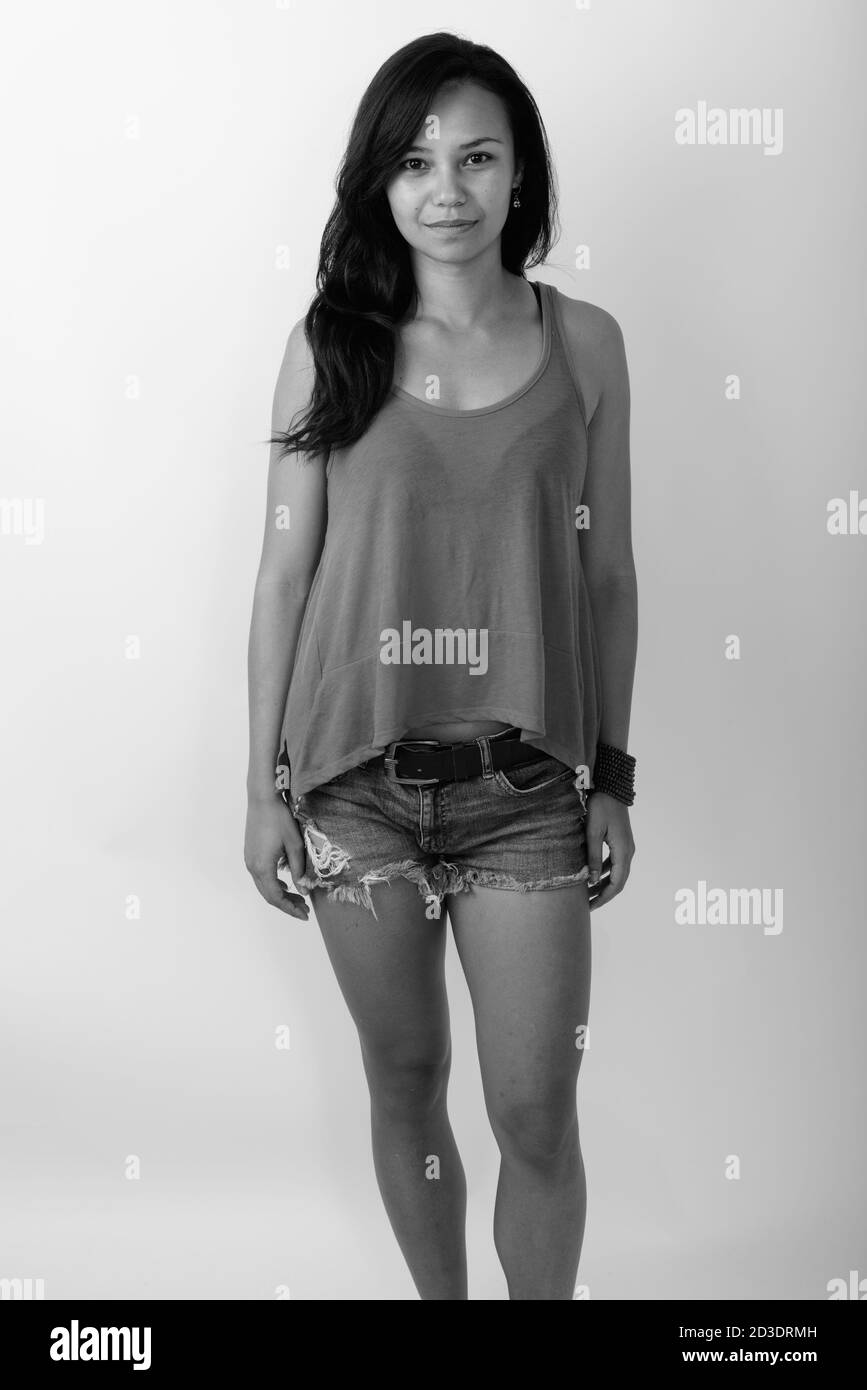 Studio shot of young Asian woman standing against white background ...