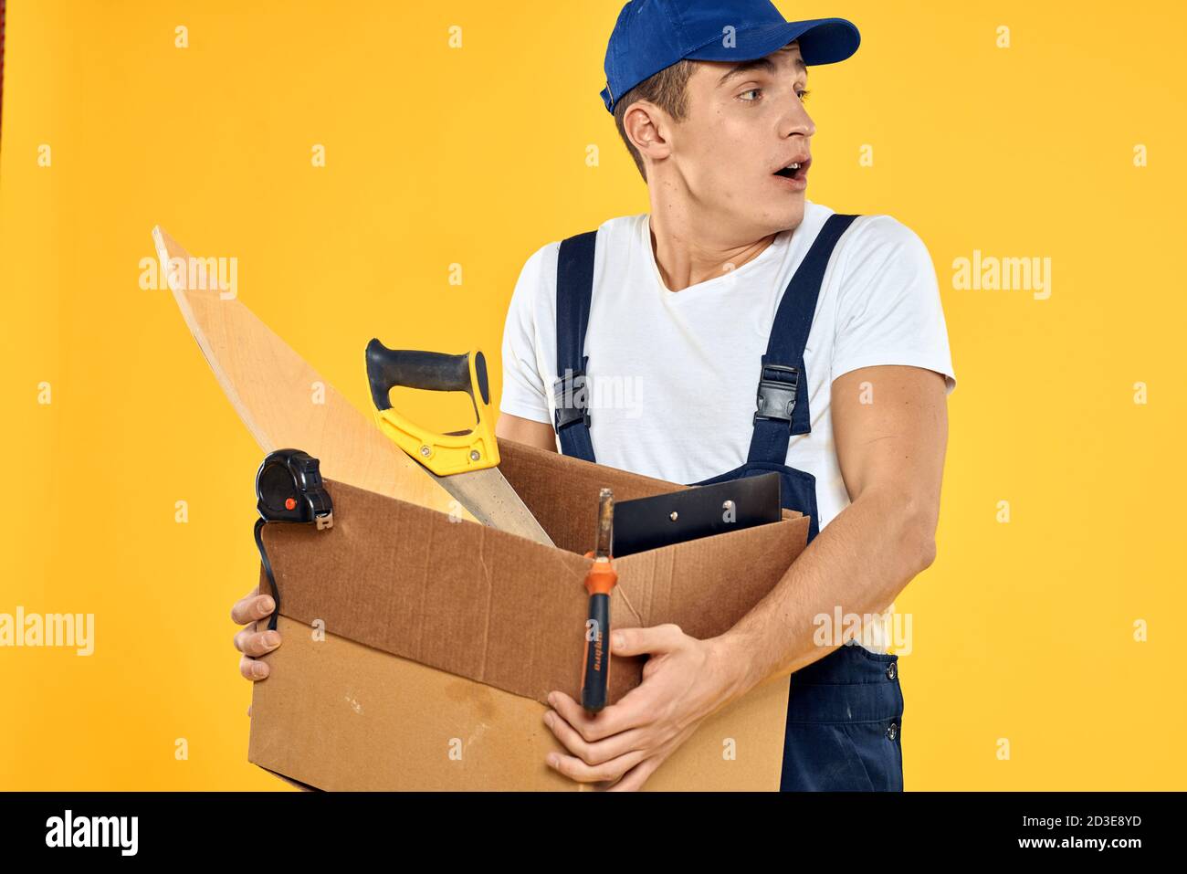 worker with box in hand tools loader yellow background Stock Photo - Alamy
