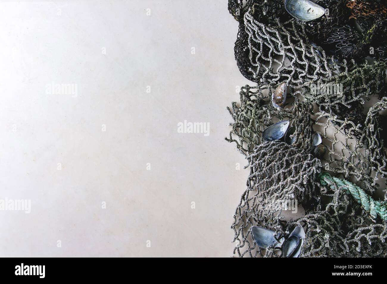 Old different sea fishing nets with empty seashells over white marble ...