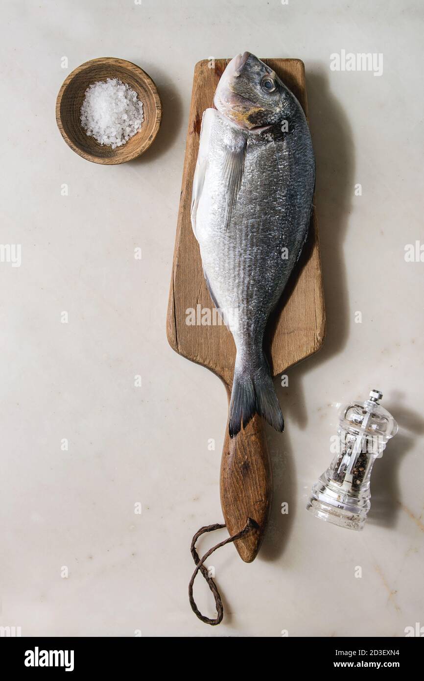 Raw uncooked gutted sea bream or dorado fish on wooden cutting board ...