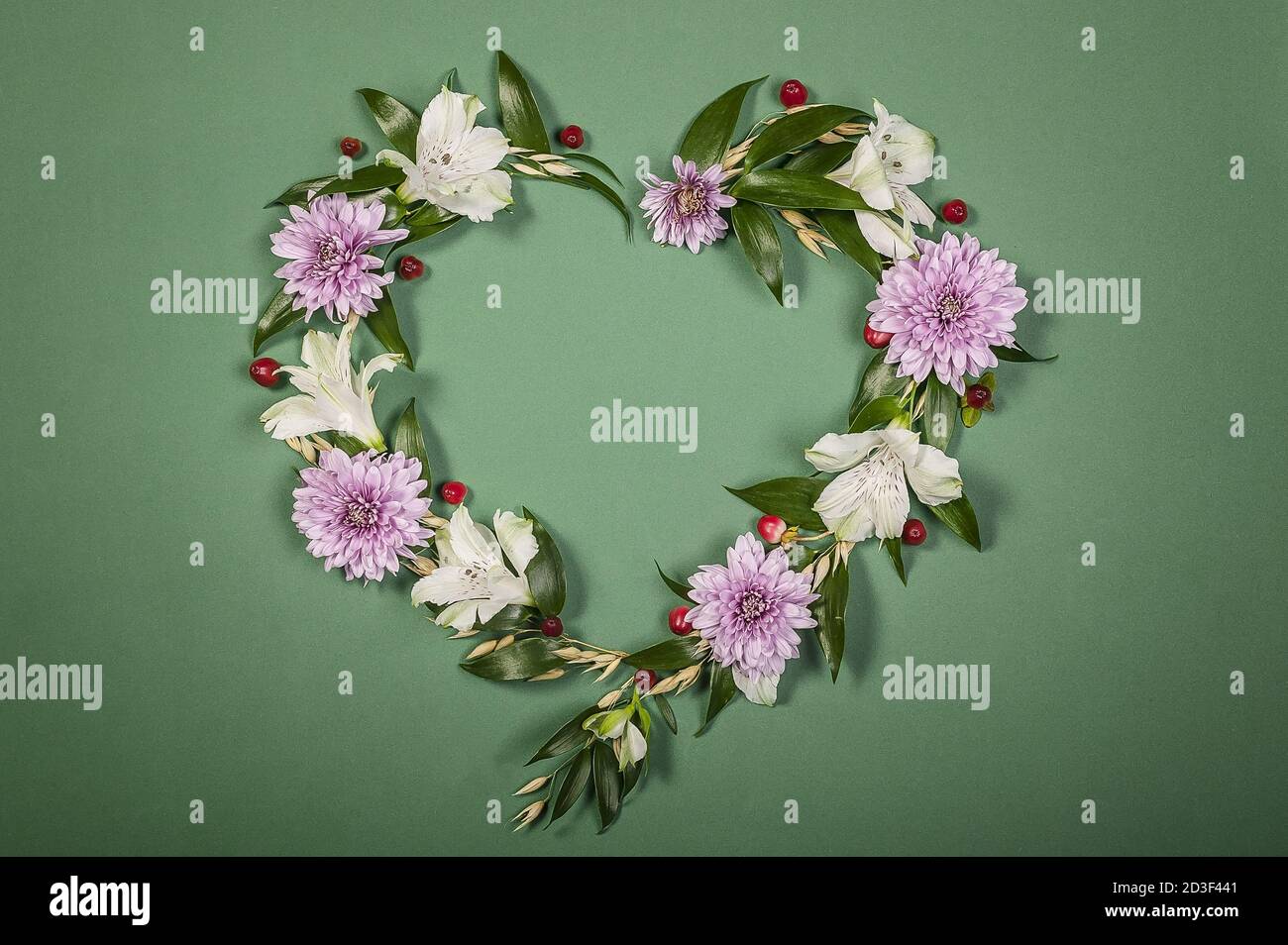 Floral frame made of leaves and flowers in the shape of a heart on a ...