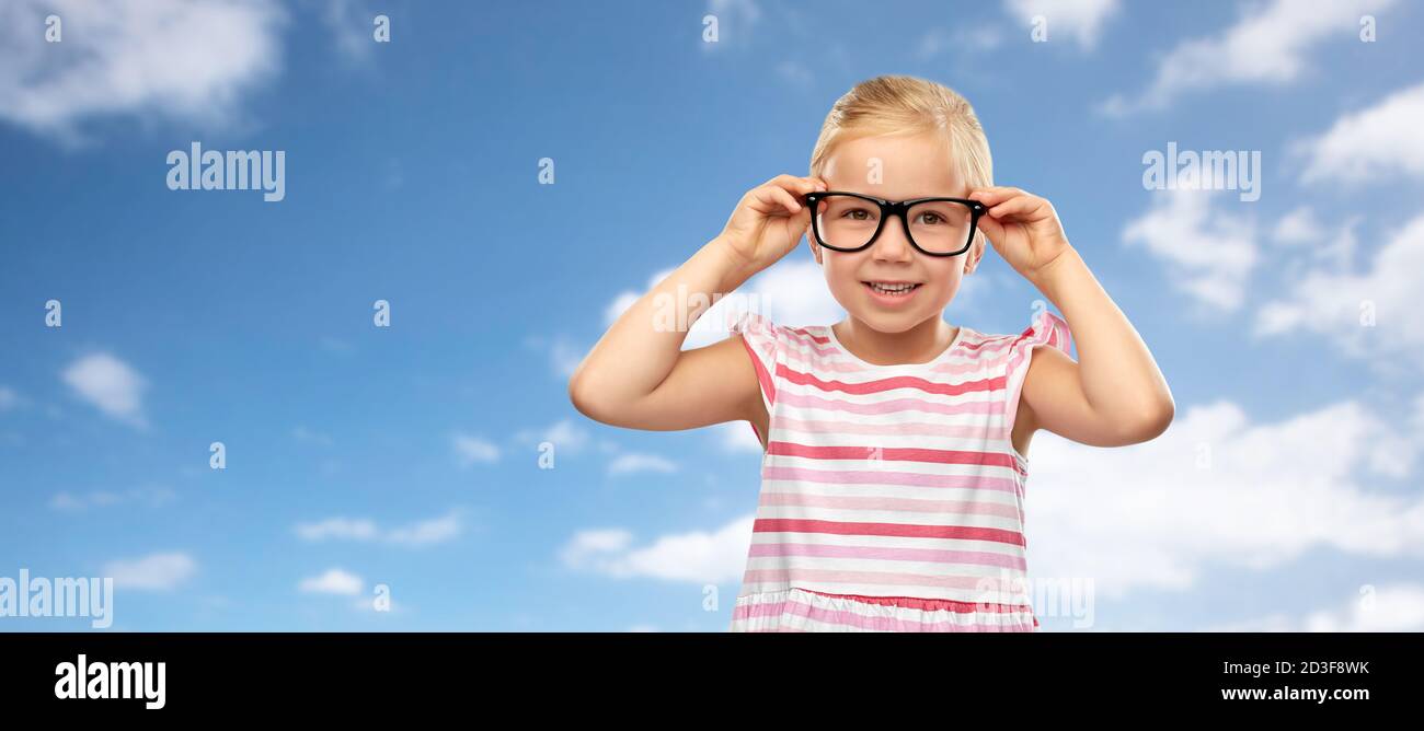 smiling little girl in glasses over sky background Stock Photo - Alamy