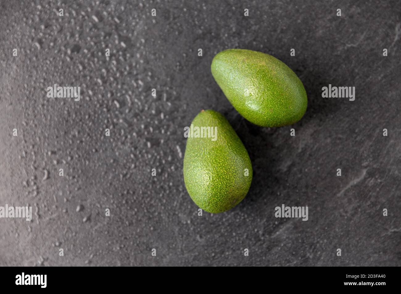 two avocados on wet slate stone background Stock Photo - Alamy
