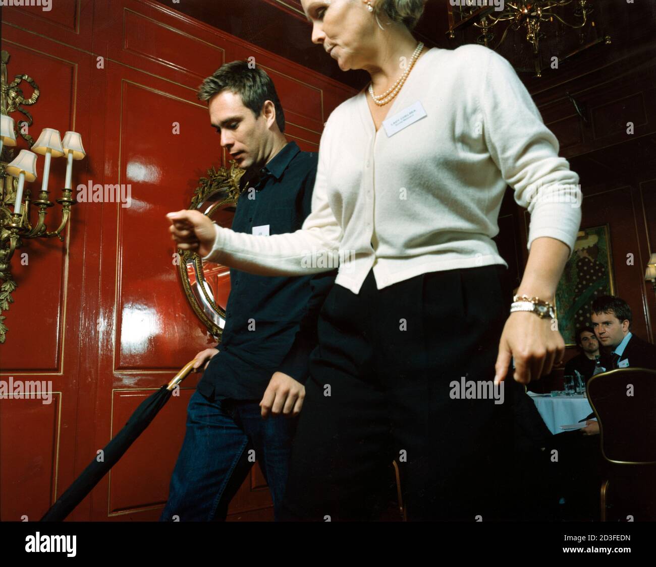 Lady Chelsea showing a finishing school trainee how to walk with an ...