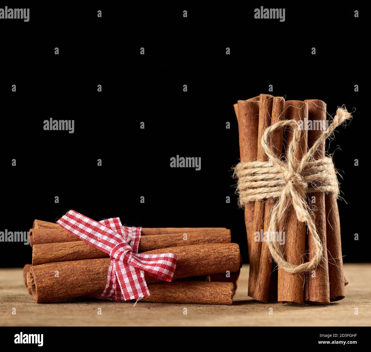 tied bunch of brown cinnamon sticks on a brown wooden background, close ...