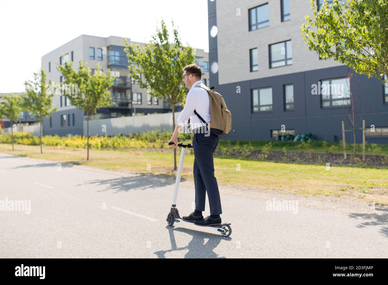 businessman with backpack riding electric scooter Stock Photo - Alamy