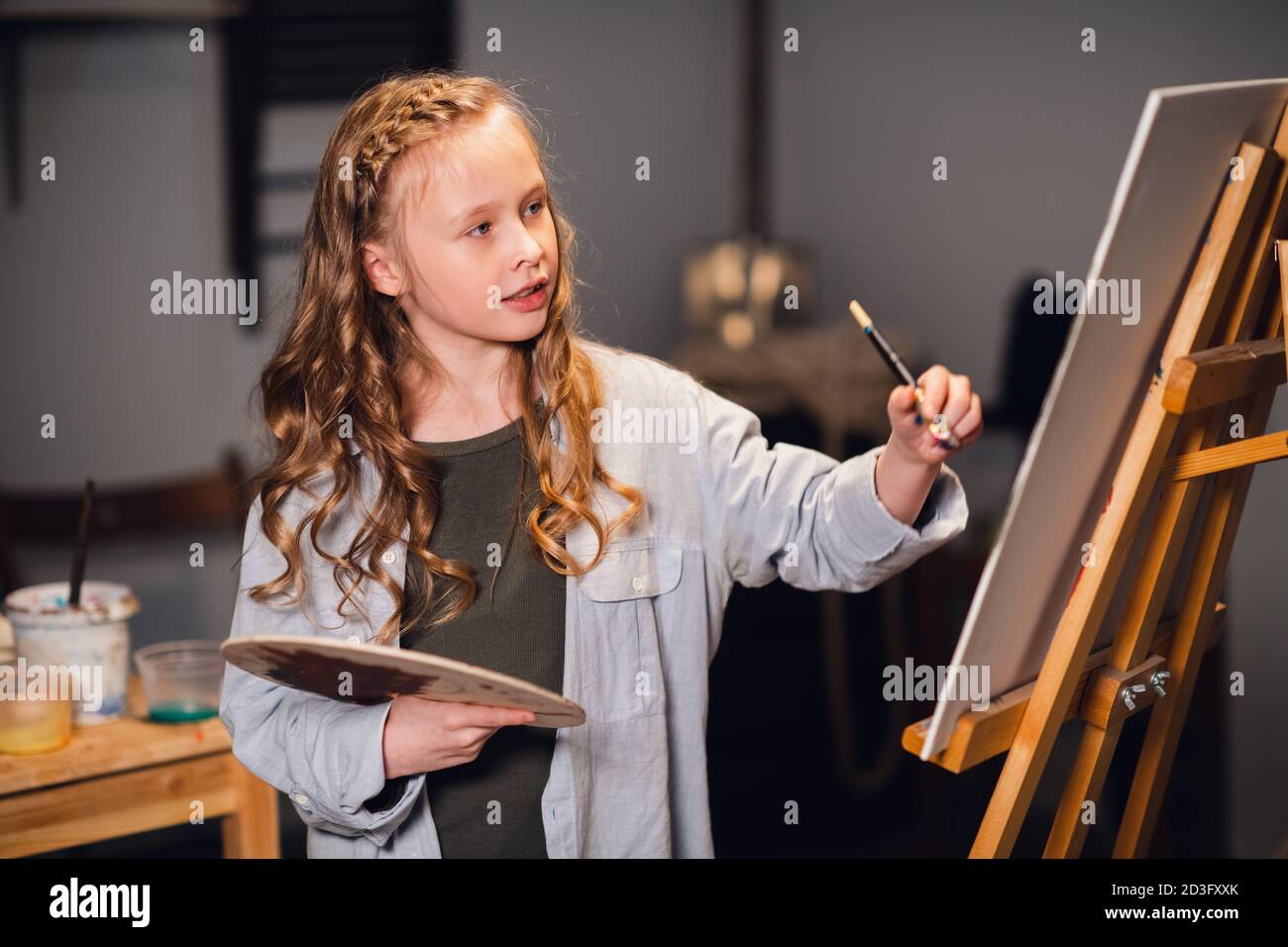 Young girl creative artist at work in a workshop. With passion draws a ...