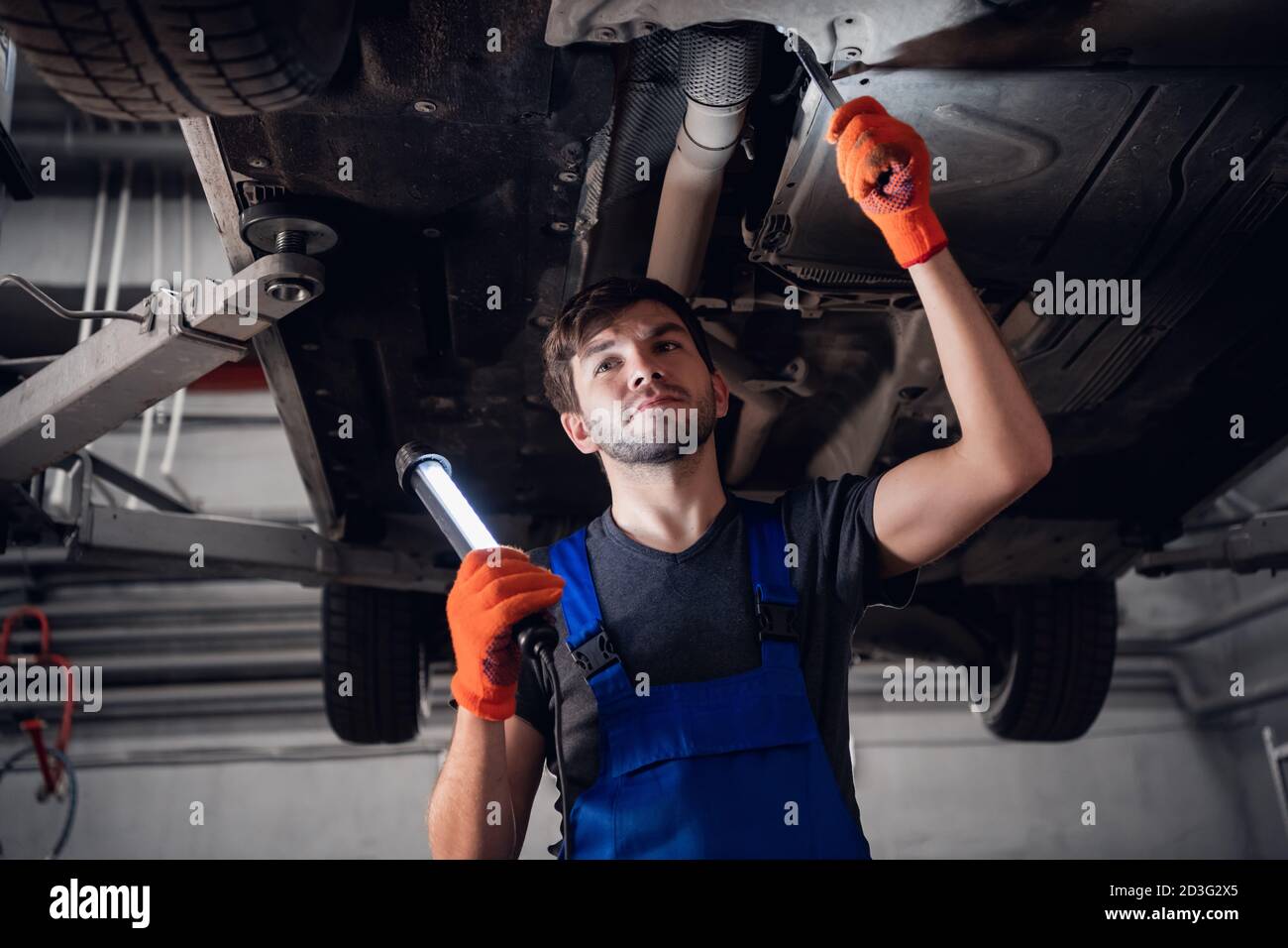 Engineer fixing car suspension and using a small flashlight Stock Photo ...