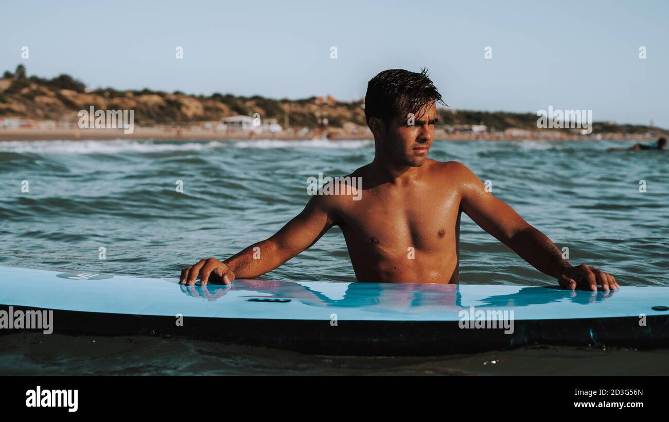 Surfer male in water leaning on his surfboard Stock Photo - Alamy