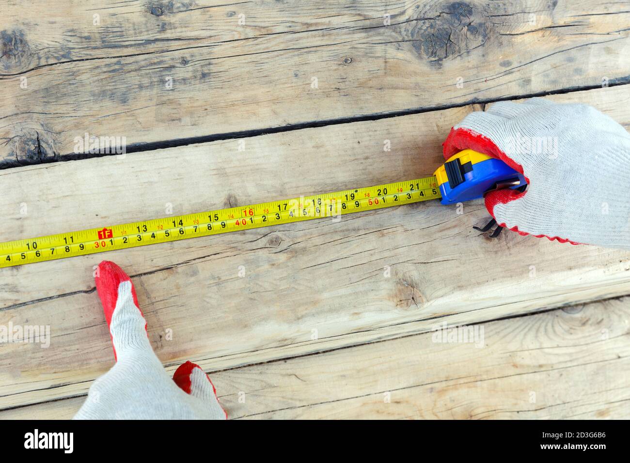 A male hand in work gloves points with the index finger to the length ...