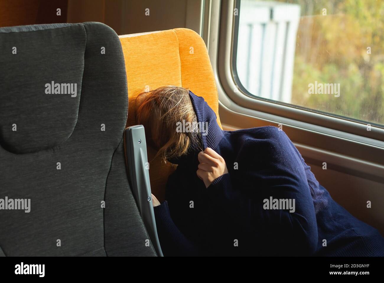 Young woman traveler sleeping inside of suburban train. She covered her ...