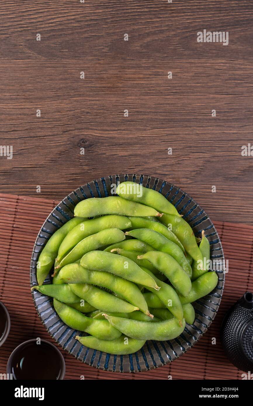 Top view of fresh cooked boiled edamame in a plate on wooden tray and ...