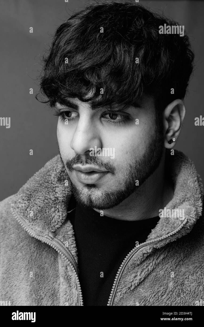 Young handsome bearded Indian man against gray background Stock Photo ...