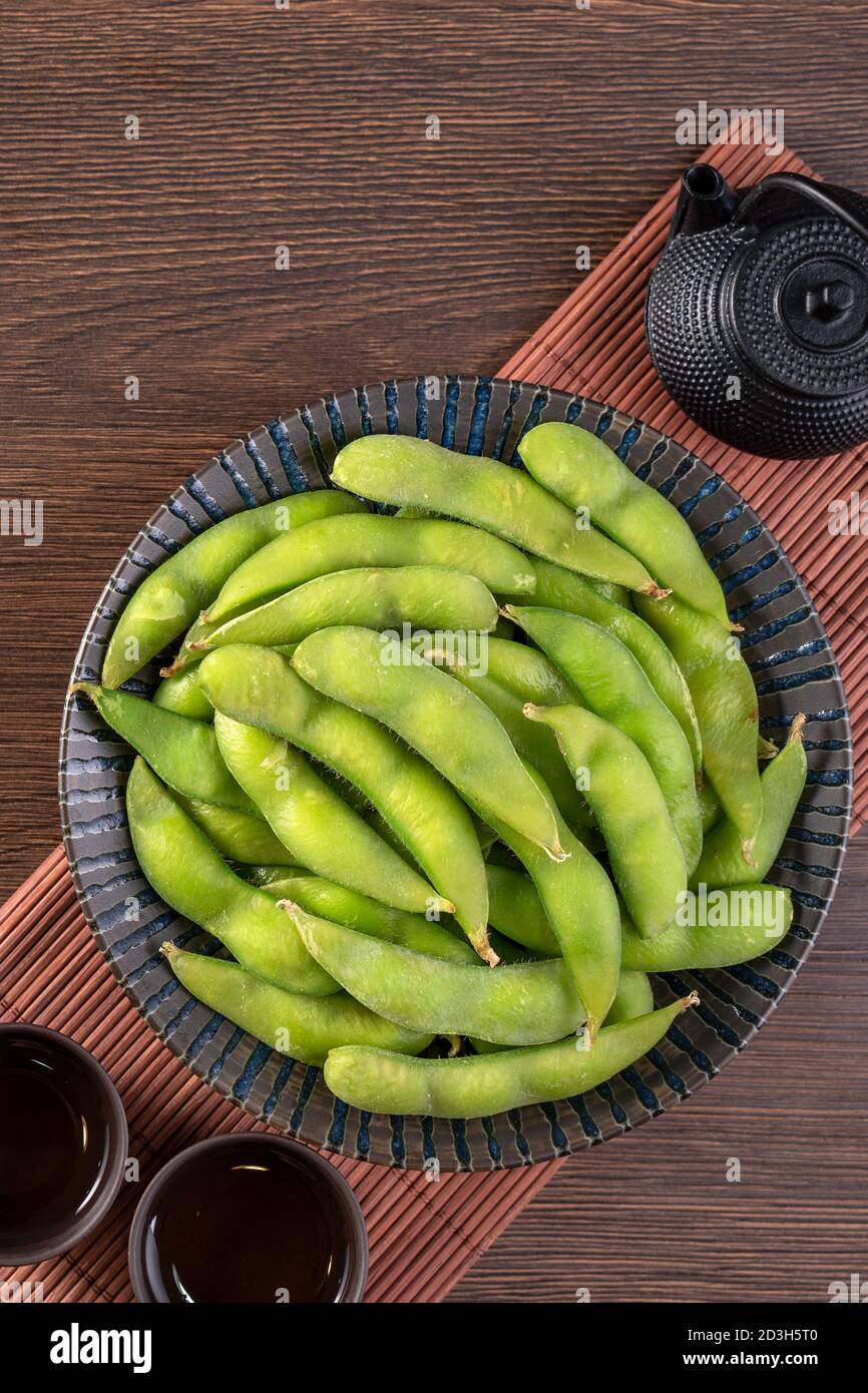 Top view of fresh cooked boiled edamame in a plate on wooden tray and ...