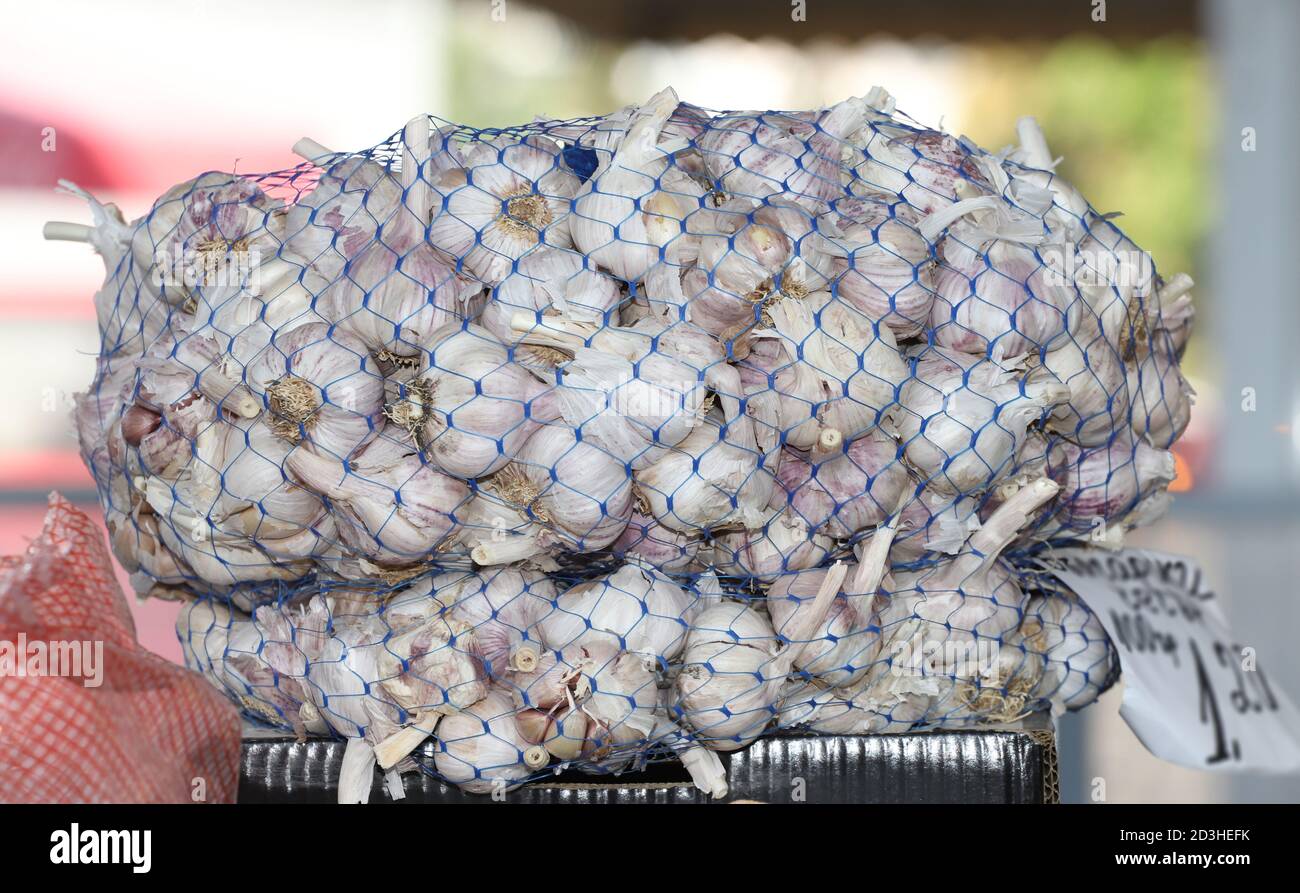 Garlic cloves in a plastic net in daylight on а market Stock Photo - Alamy