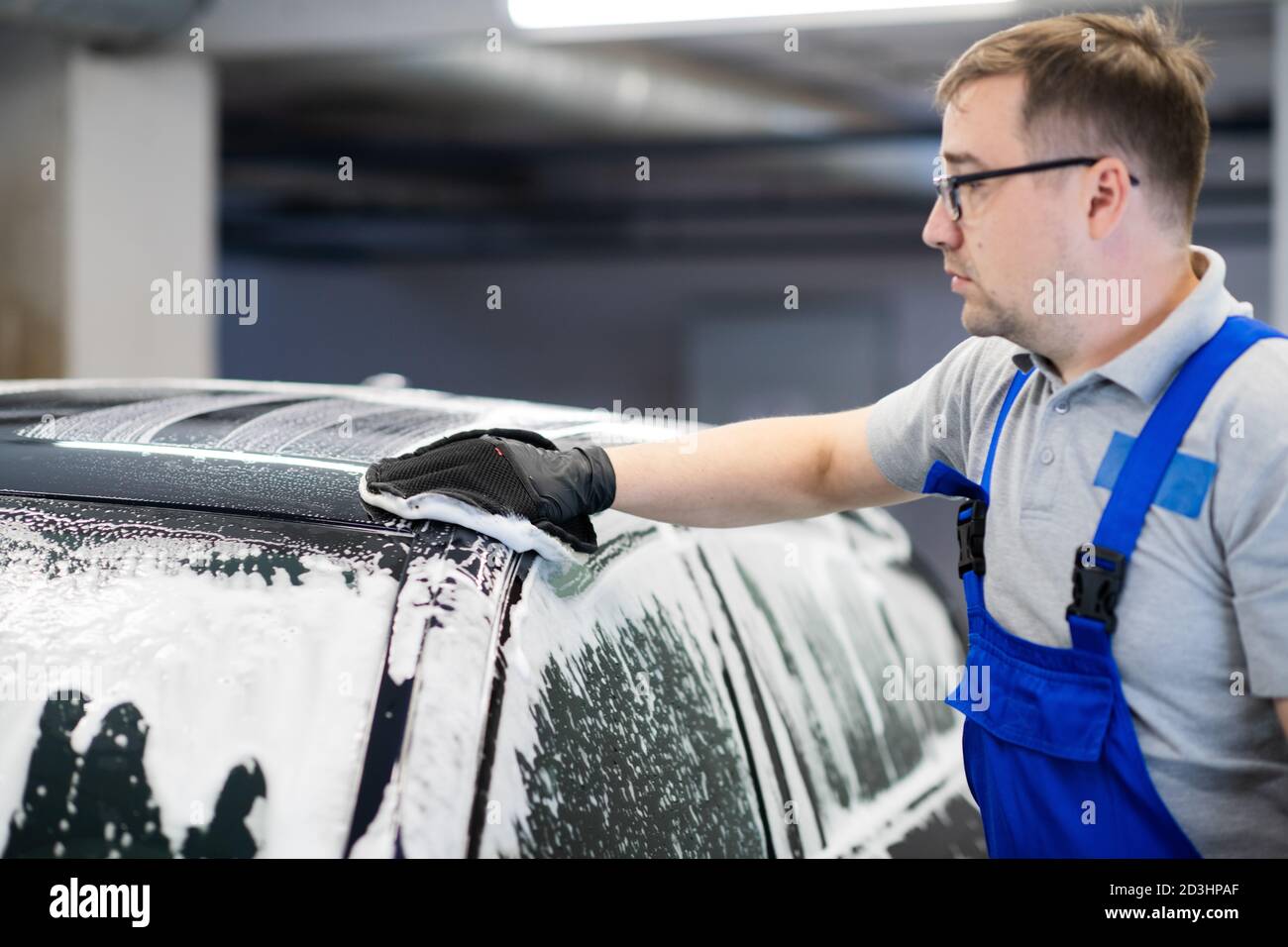 Man after washing wipes black car with a rag at car wash. Male hand and ...