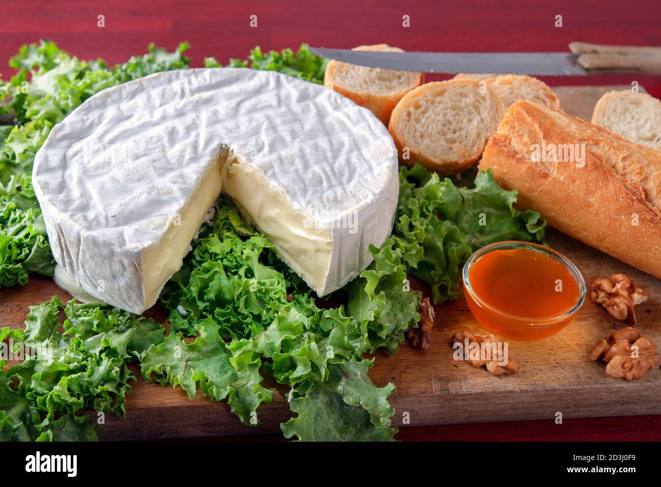 rustic Camembert cheese on wooden board with green salade with honey ...