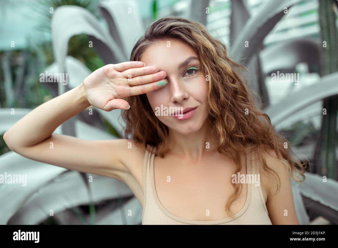 Pretty young woman closing one eye with her hand Stock Photo - Alamy