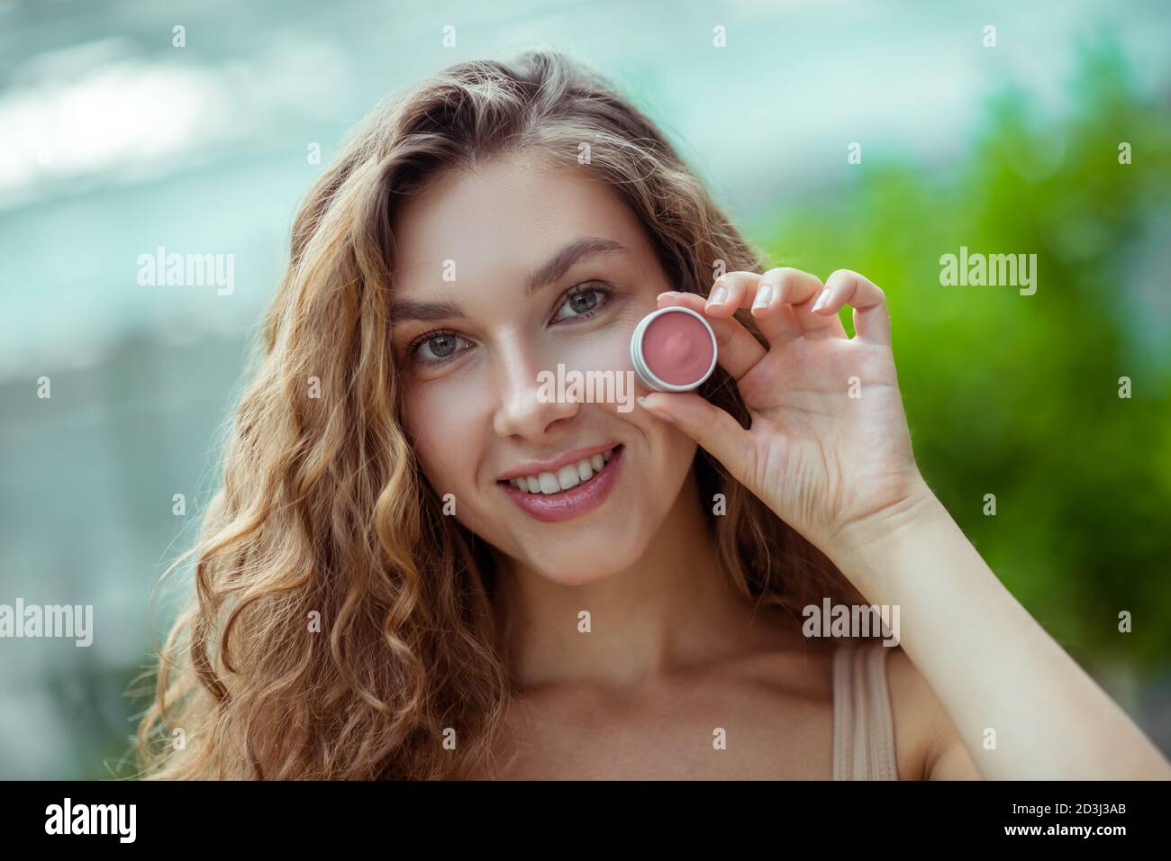 Pretty young woman holding lip balm in her hand Stock Photo - Alamy