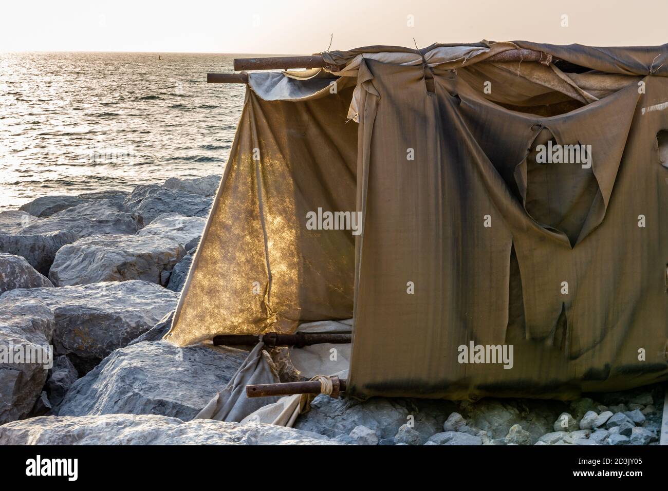 Temporary fabric tent made of old rugs standing on a stone jetty, with ...