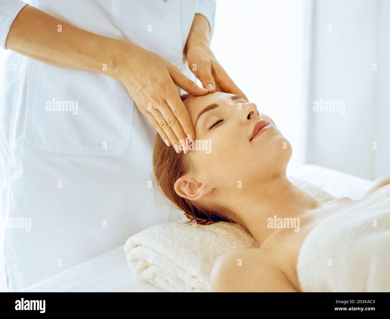 Beautiful woman enjoying facial massage with closed eyes in spa center ...
