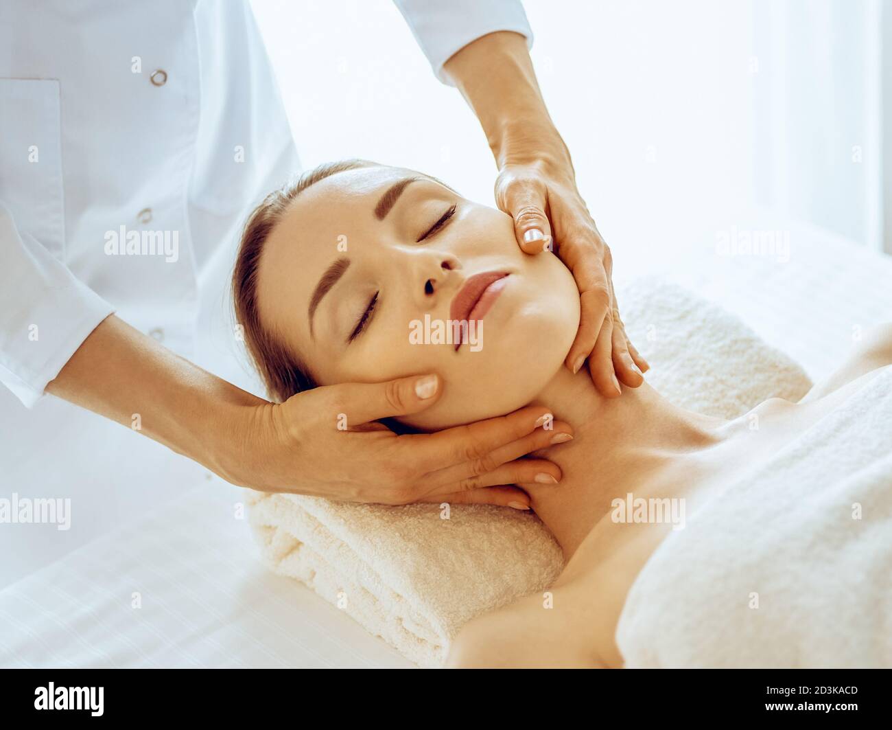 Beautiful woman enjoying facial massage with closed eyes in spa center ...