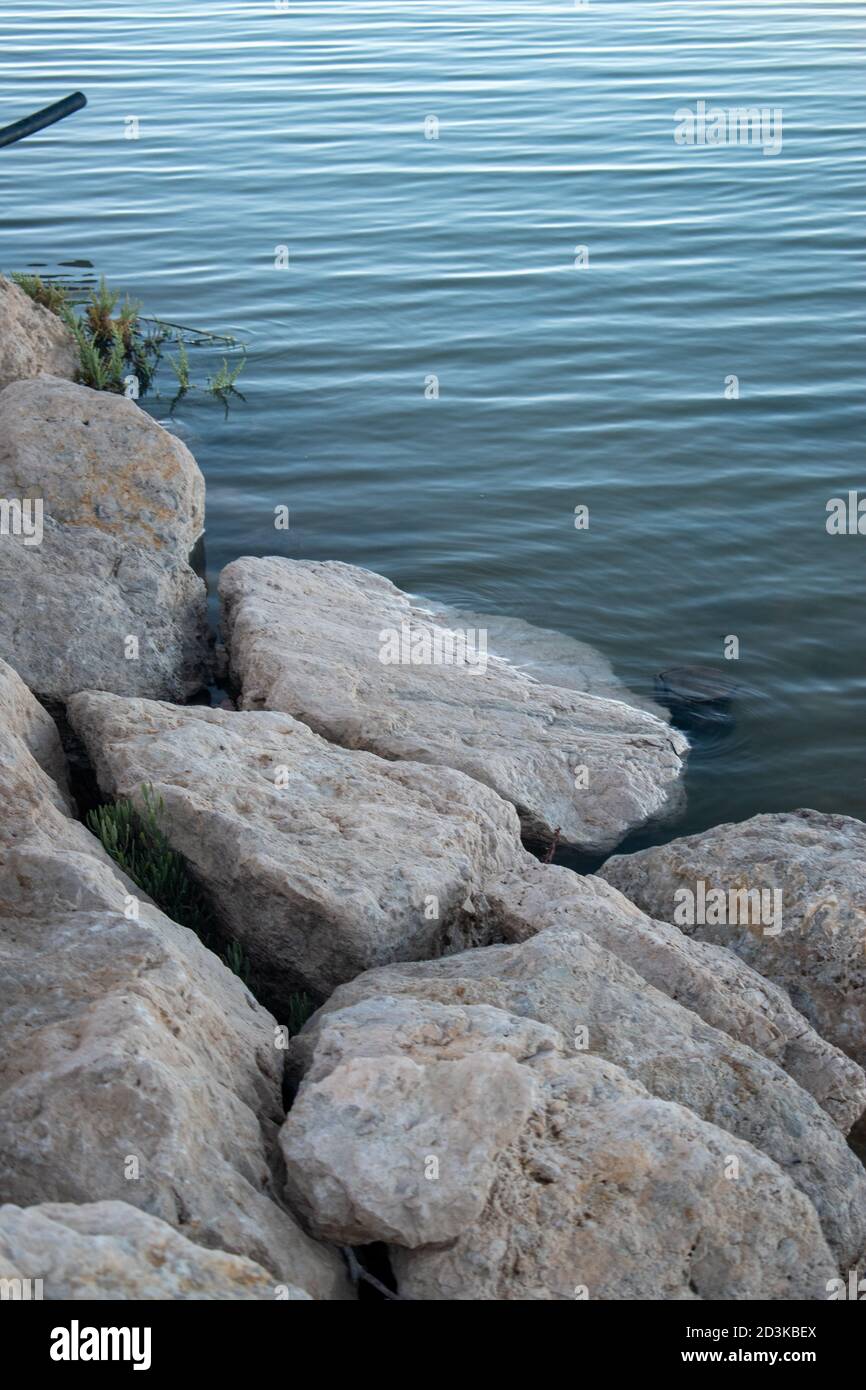 vertical photograph of a pile of large rocks that make up the shore of ...