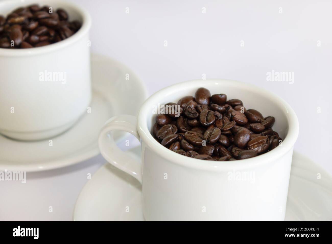 Coffee beans in two coffee cups , on white isolated background.Closeup ...
