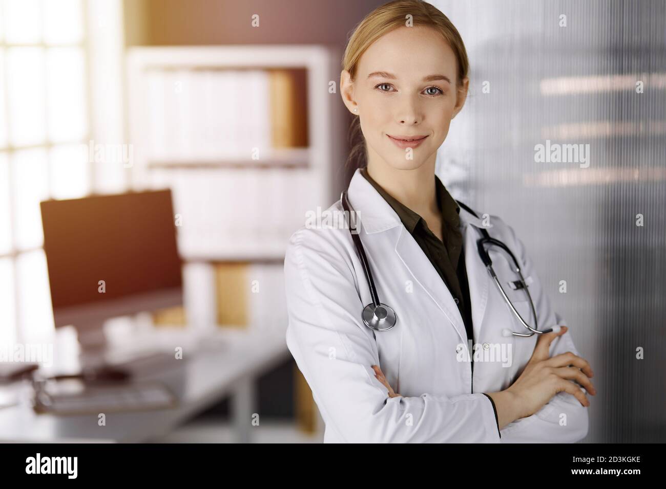 Cheerful smiling female doctor standing in sunny clinic. Portrait of ...