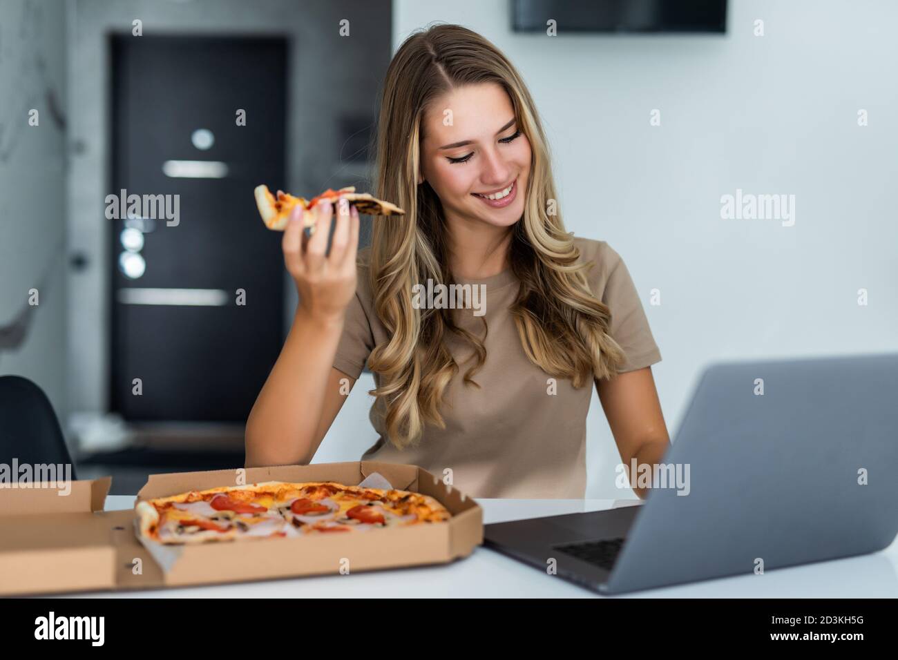 Overworked woman taking a break and eating pizza, working from home on ...