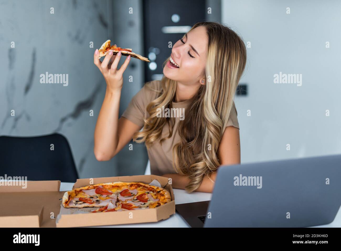 Overworked woman taking a break and eating pizza, working from home on ...